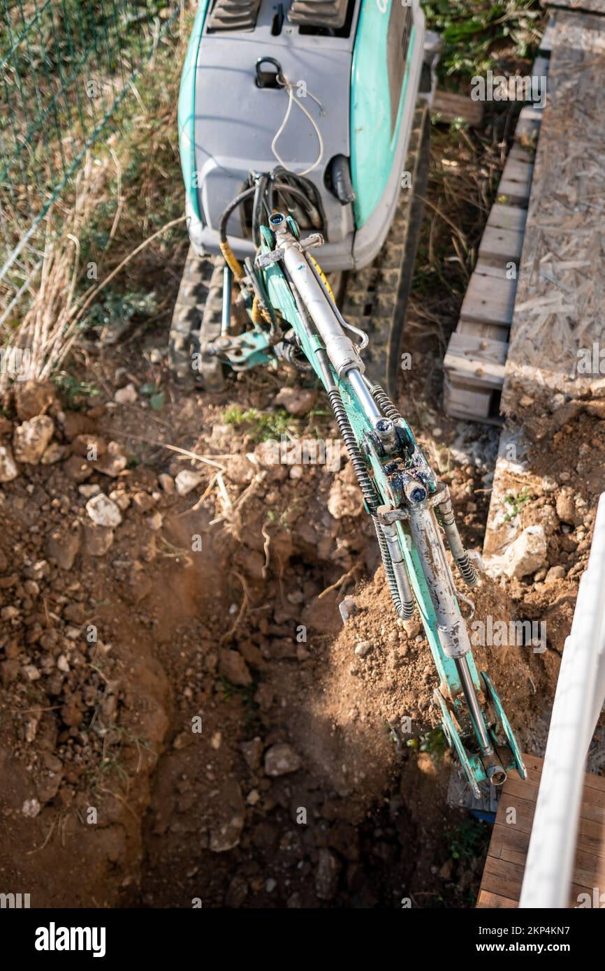 Mini excavator digs a trench to lay pipes. Close up of an excavator ...