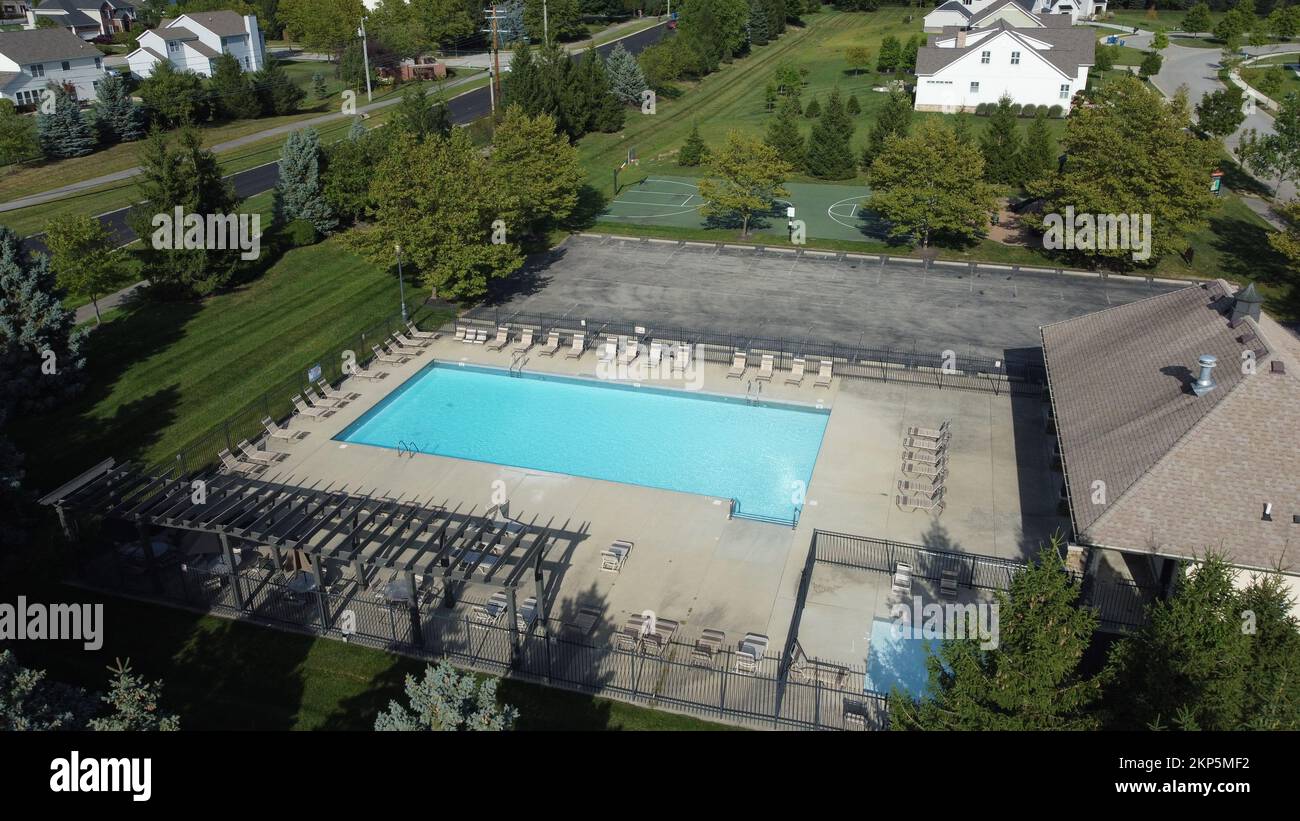 A top view of a neighborhood swimming pool beside basketball court in ...