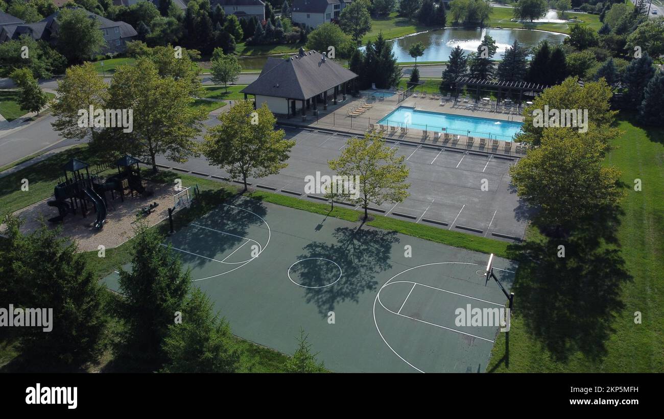 A top view of a neighborhood swimming pool beside basketball court in ...