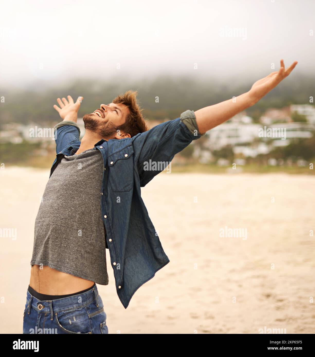 Let the sea set you free. a carefree young man throwing his arms back ...