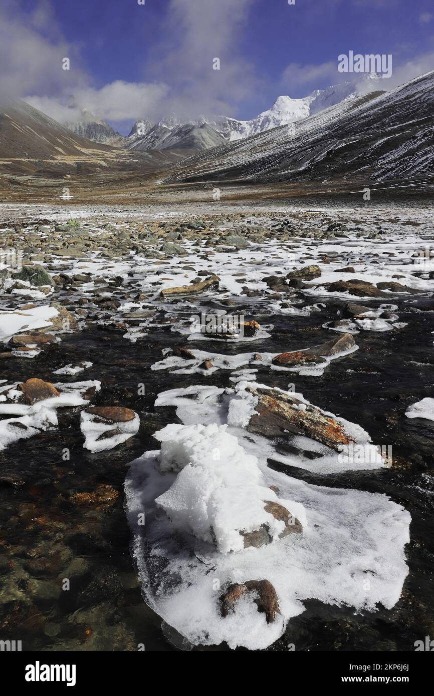 frozen mountain stream flowing through the scenic alpine valley at ...