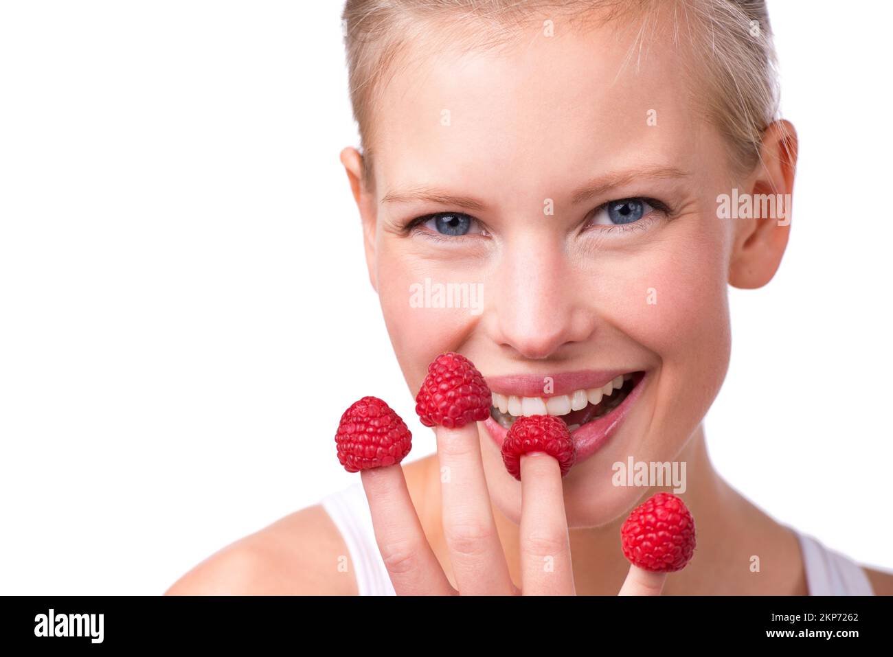 Finger food fun. a beautiful young woman playfully eating raspberries ...