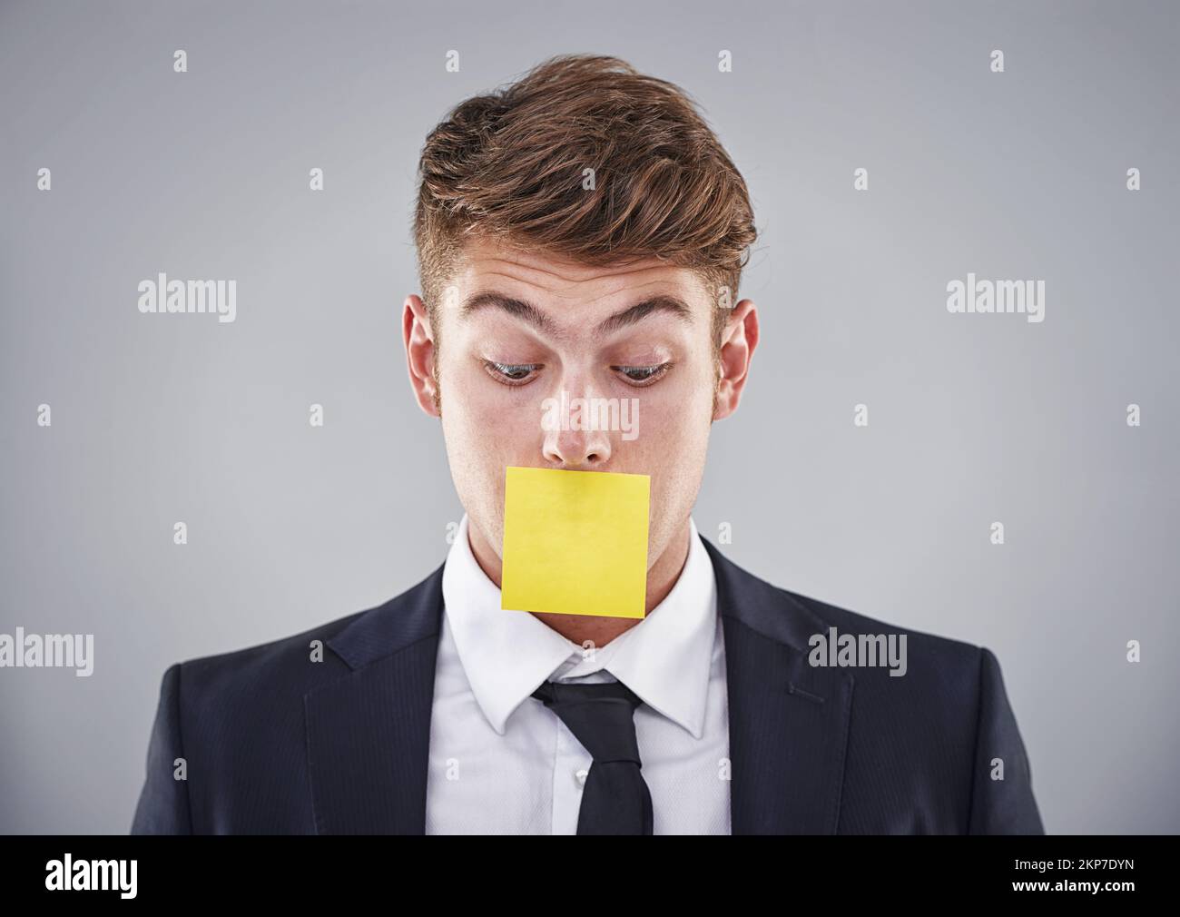 Silenced by work. a business man with a post it note stuck to his mouth ...