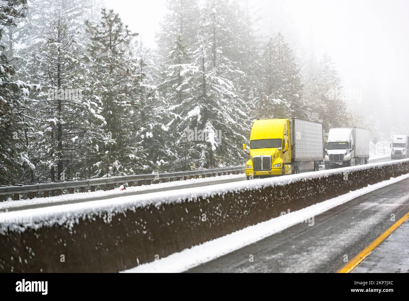 Convoy of industrial big rigs semi trucks with turned on headlights and ...