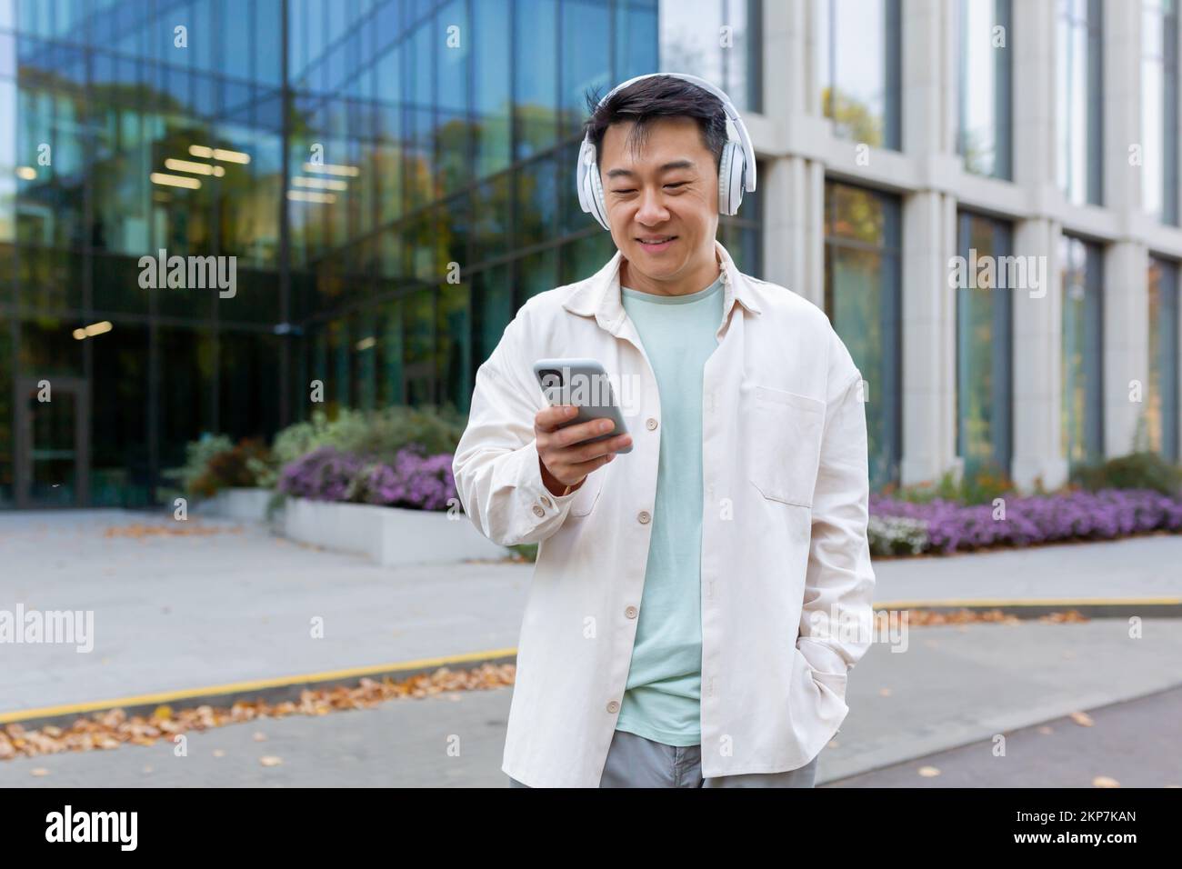 Asian man in casual clothes listening to music in headphones smiling ...