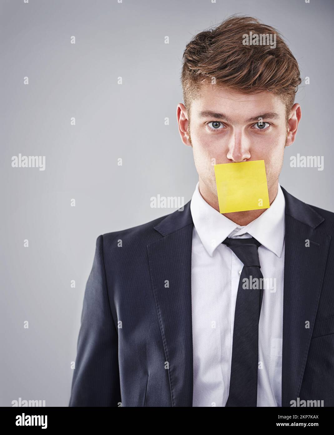 Silenced by work. a business man with a post it note stuck to his mouth ...
