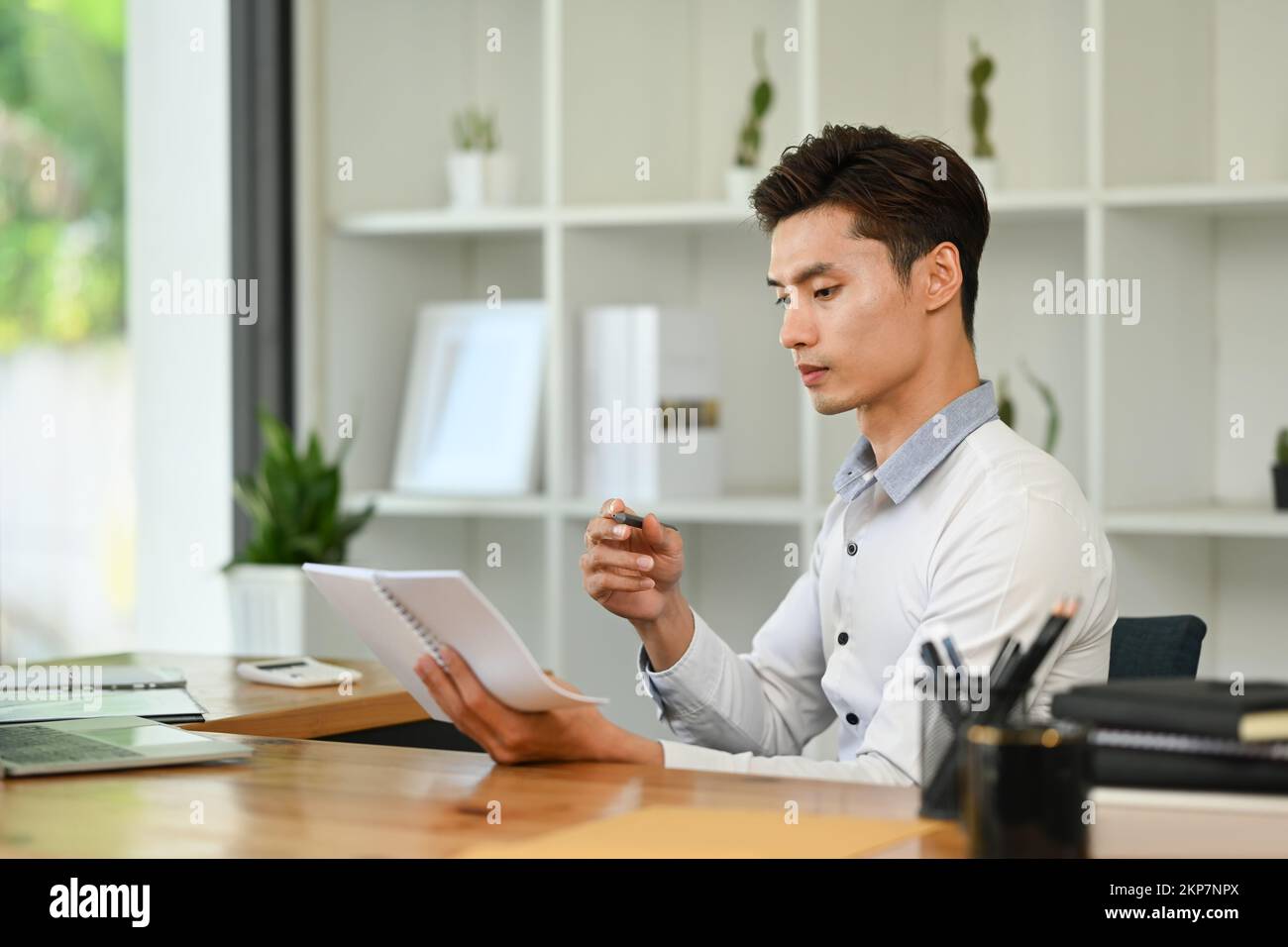 Side view of male manager analyzing weekly schedule in his notebook ...