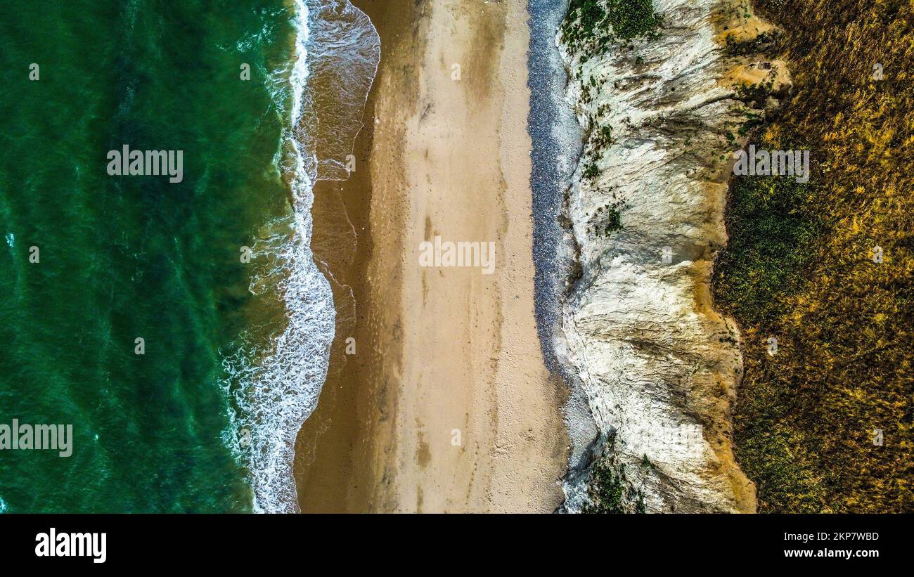 A bird's eye view of a rocky cliff near a wavy ocean Stock Photo - Alamy