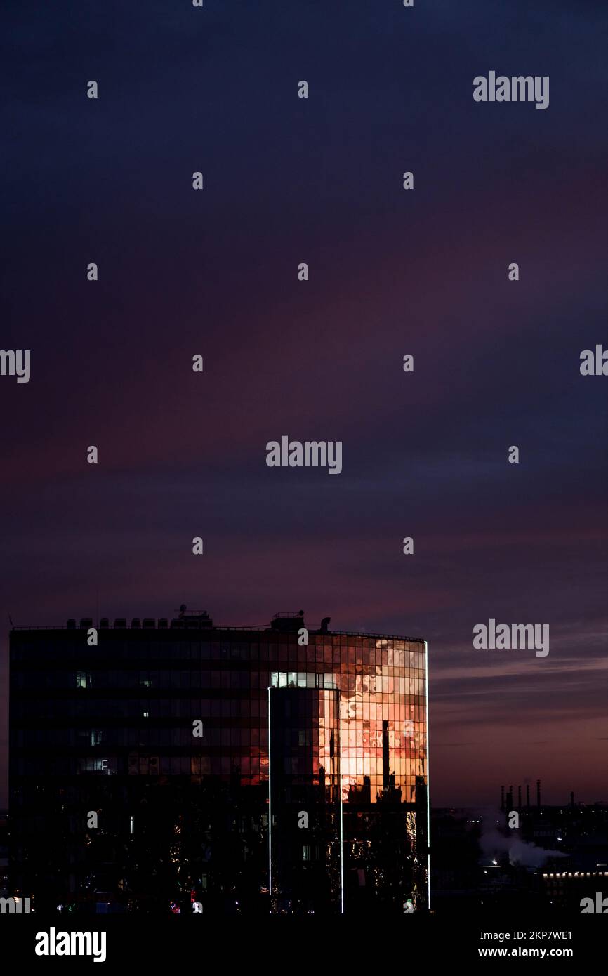 Sunset is reflected in the glass of a commercial building. business ...