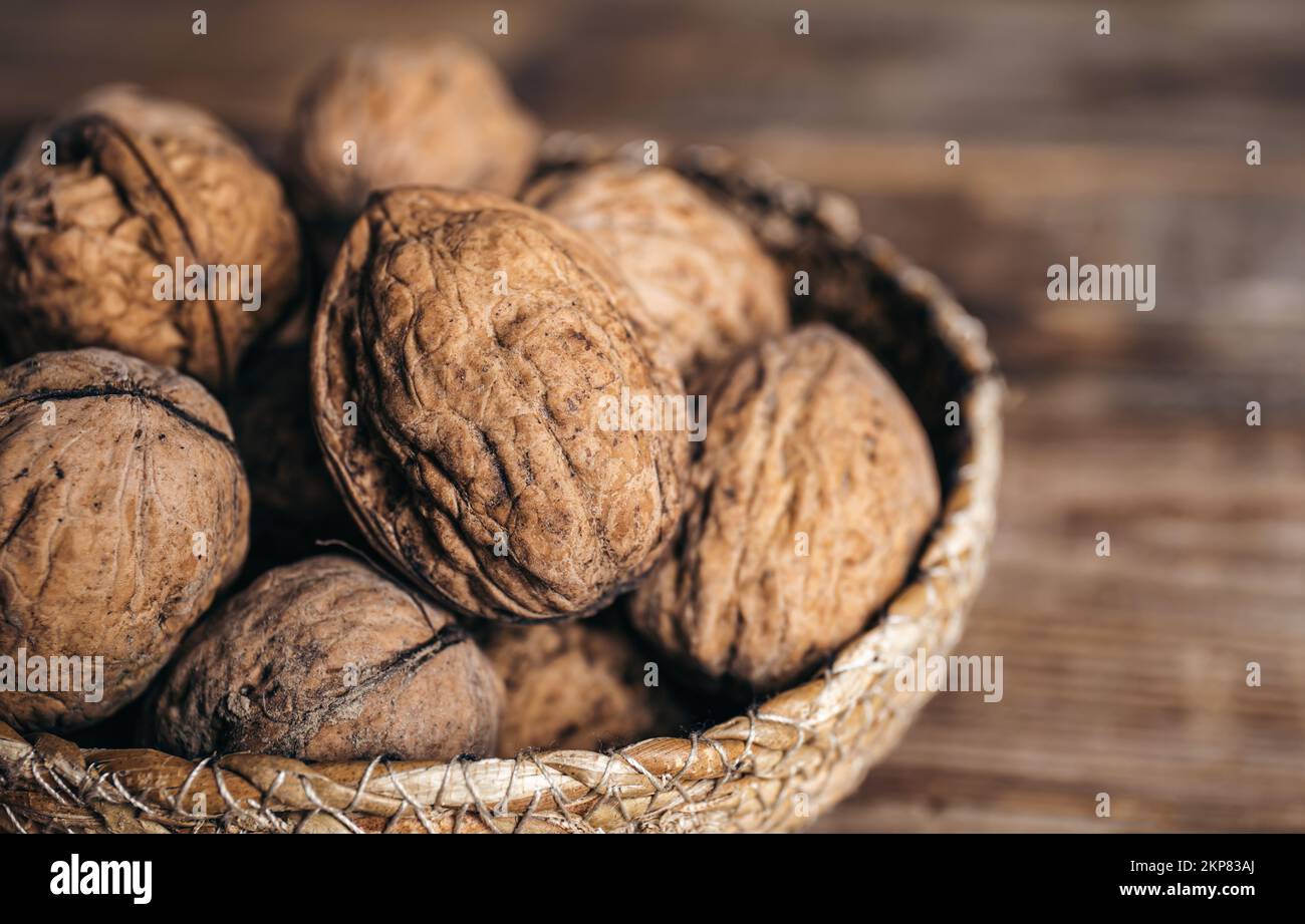 Close-up, whole walnuts in a wicker bowl on a wooden background Stock ...