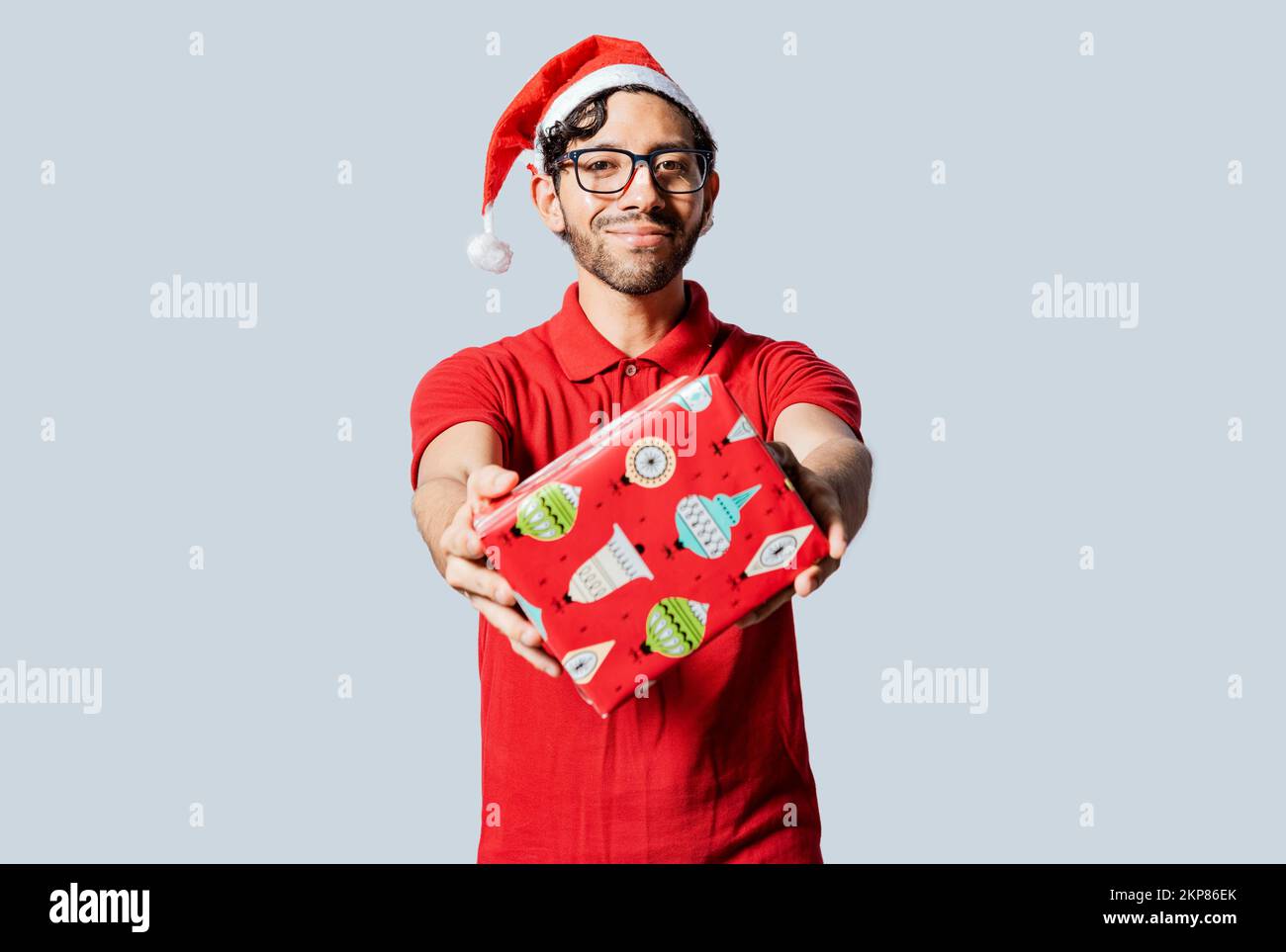 Smiling guy in christmas hat offering you a christmas gift box ...