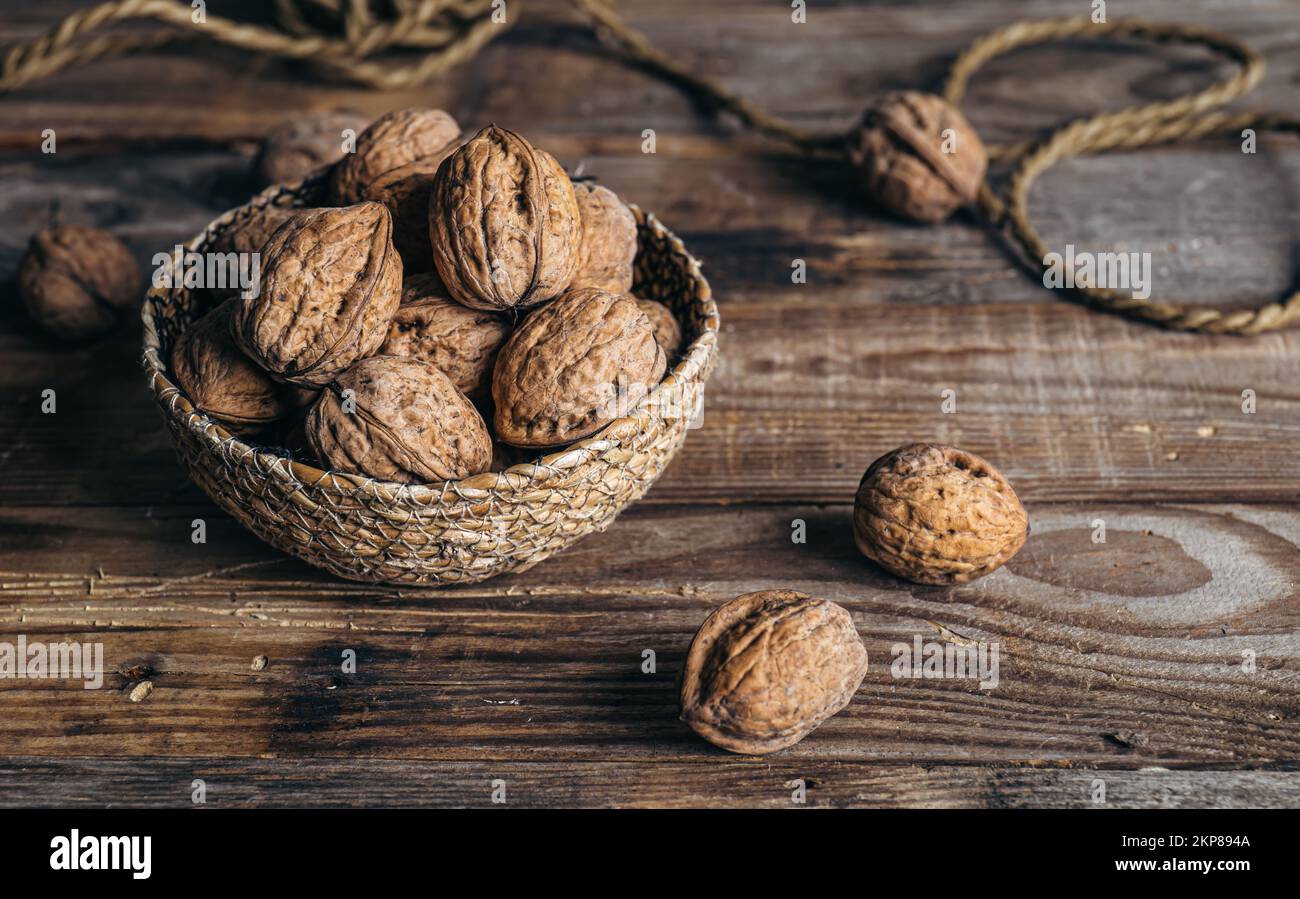 Close-up, whole walnuts in a wicker bowl on a wooden background Stock ...