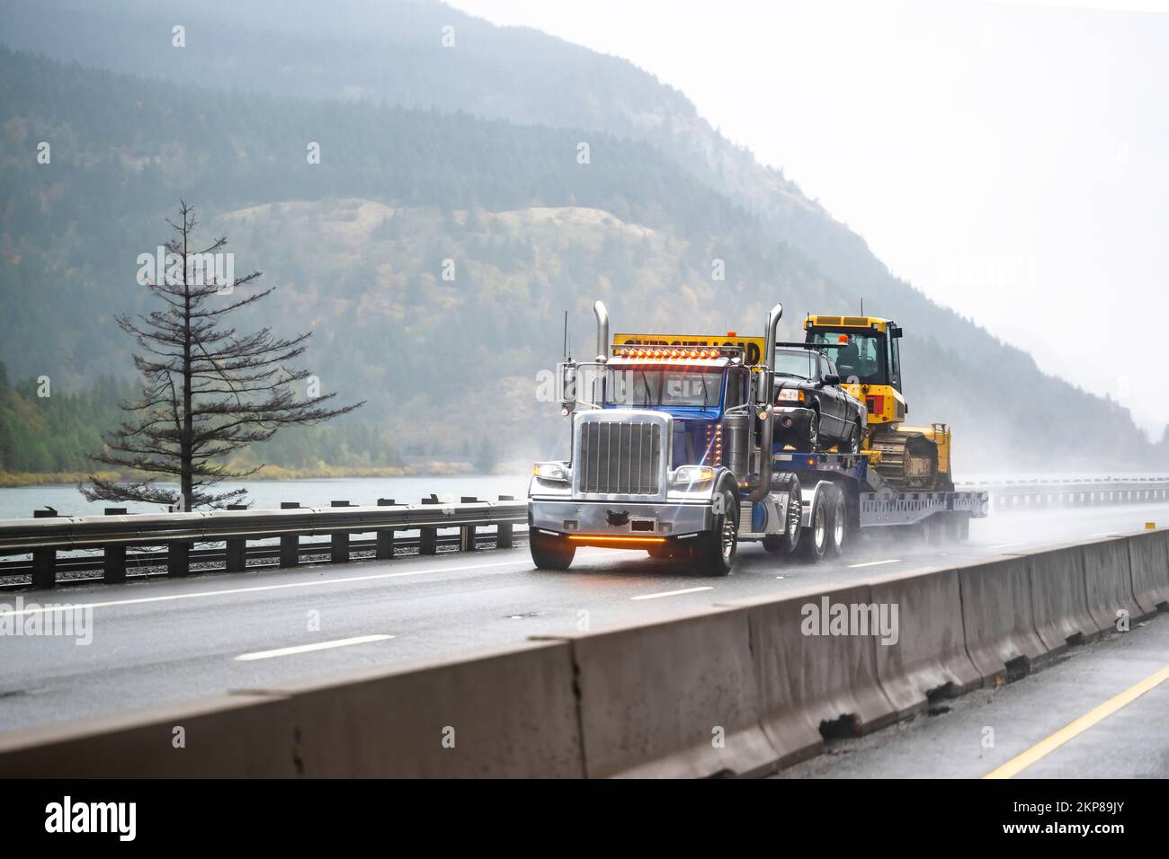 Bright blue powerful big rig classic semi truck tractor with oversize ...