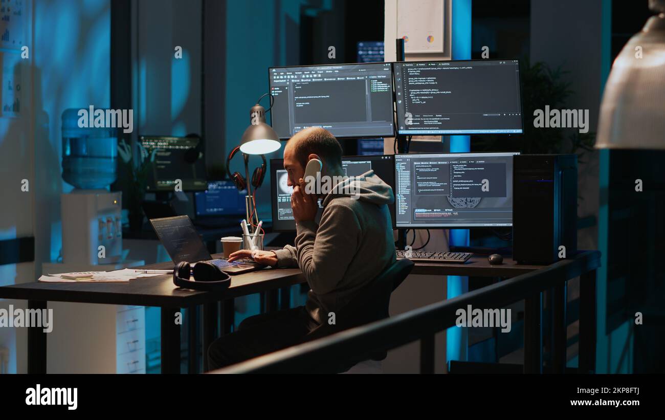 Young adult coder talking on landline phone at night, answering phone ...