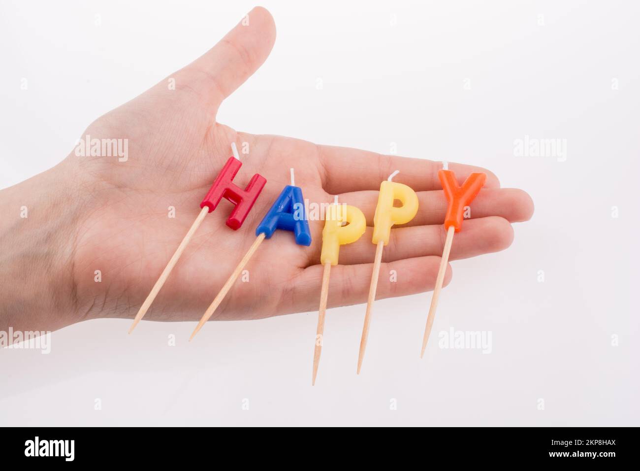 Color candles on sticks write the word happy Stock Photo - Alamy
