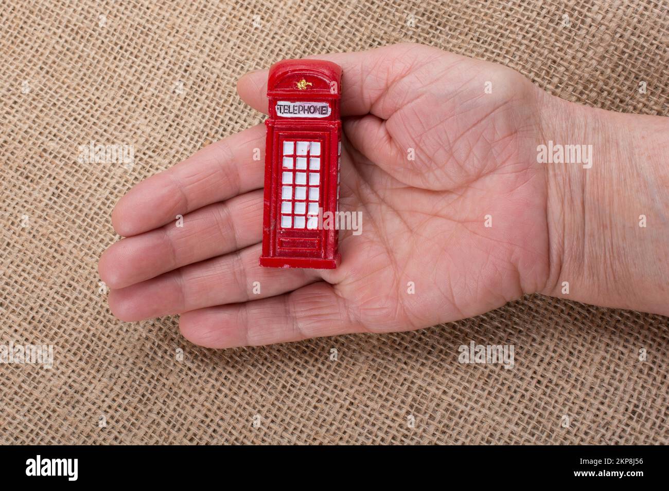 Hand holding a phone booth on a brown background Stock Photo - Alamy