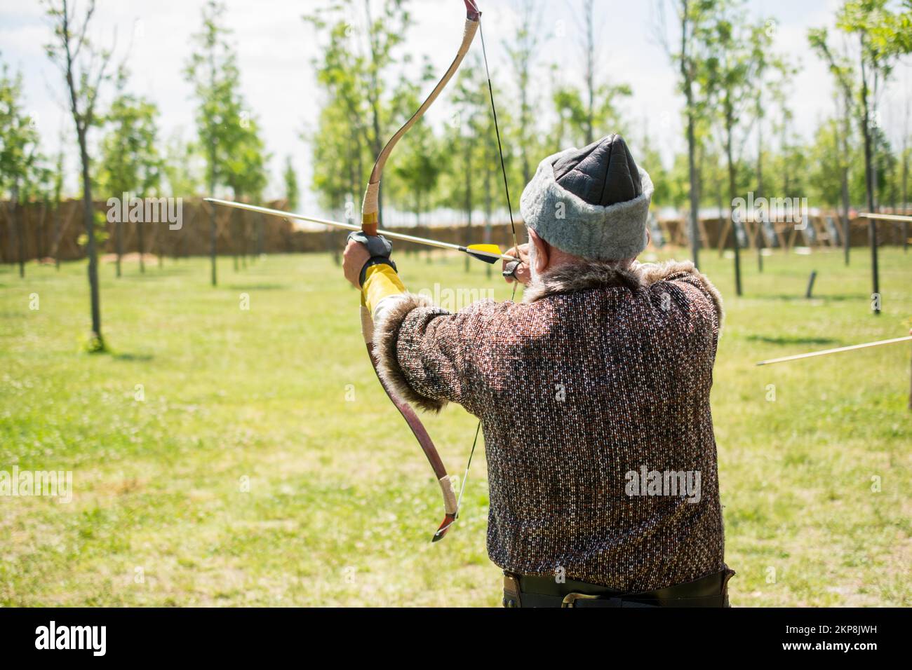 Archer with bow in traditional clothes shooting an arrow Stock Photo ...