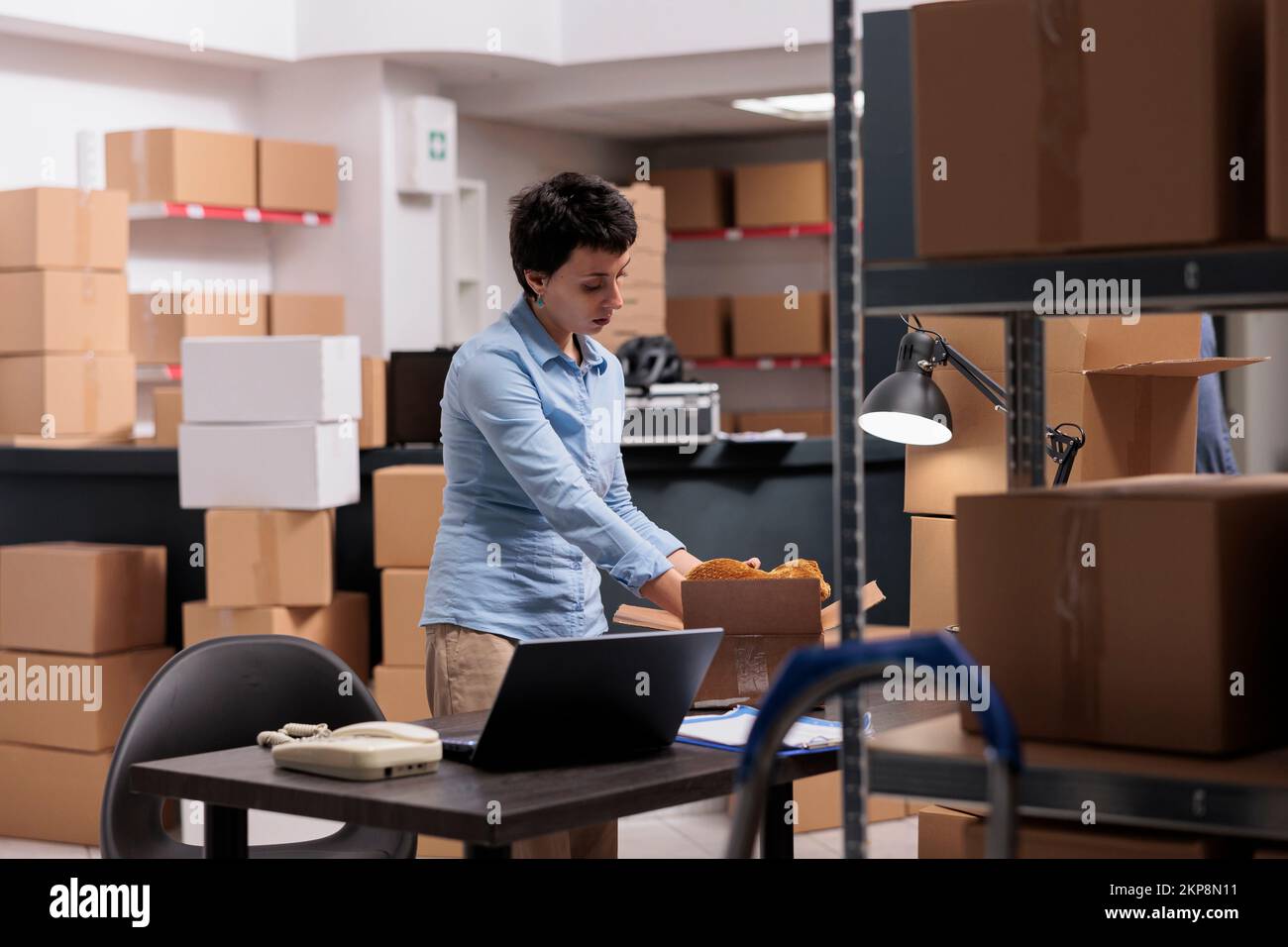Supervisor putting trendy blouse in cardboard boxes preparing customers ...