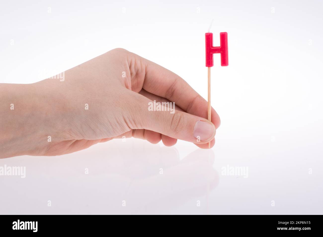 Color candle in hand on sticks writes the letter H Stock Photo - Alamy