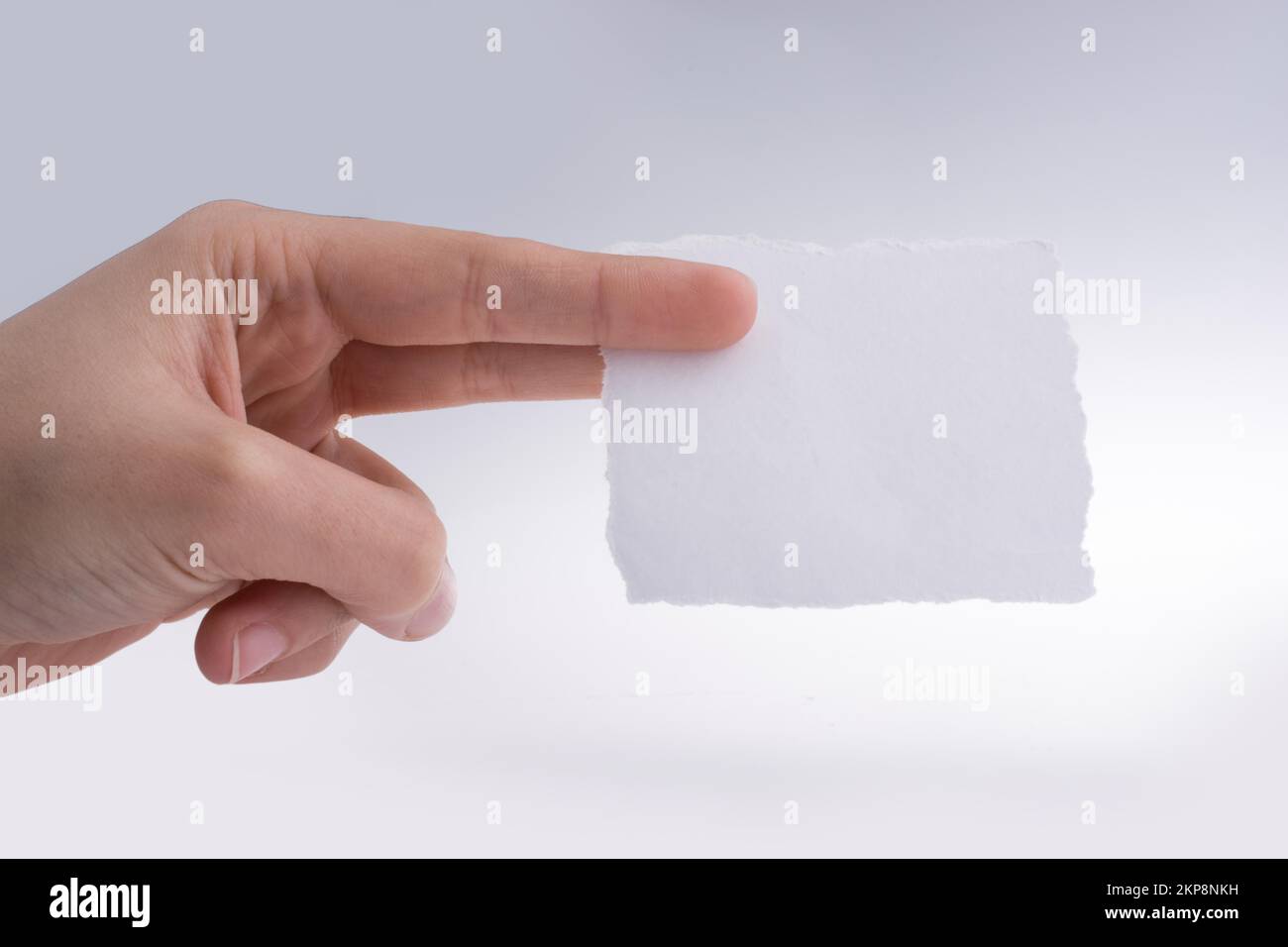 Hand holding a a piece of torn paper on a white background Stock Photo ...