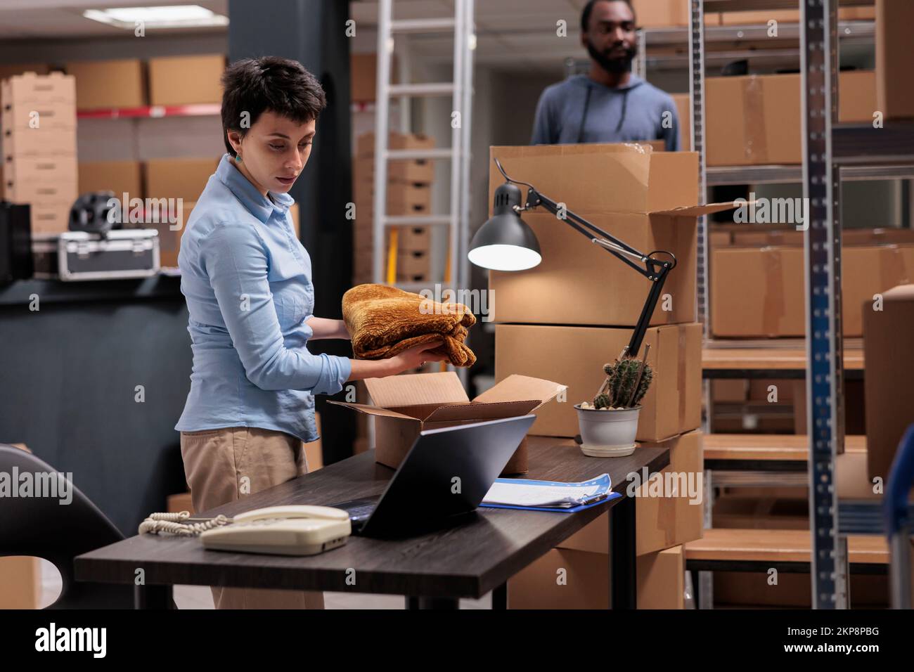 Employee putting trendy clothes in cardboard boxes preparing clients ...