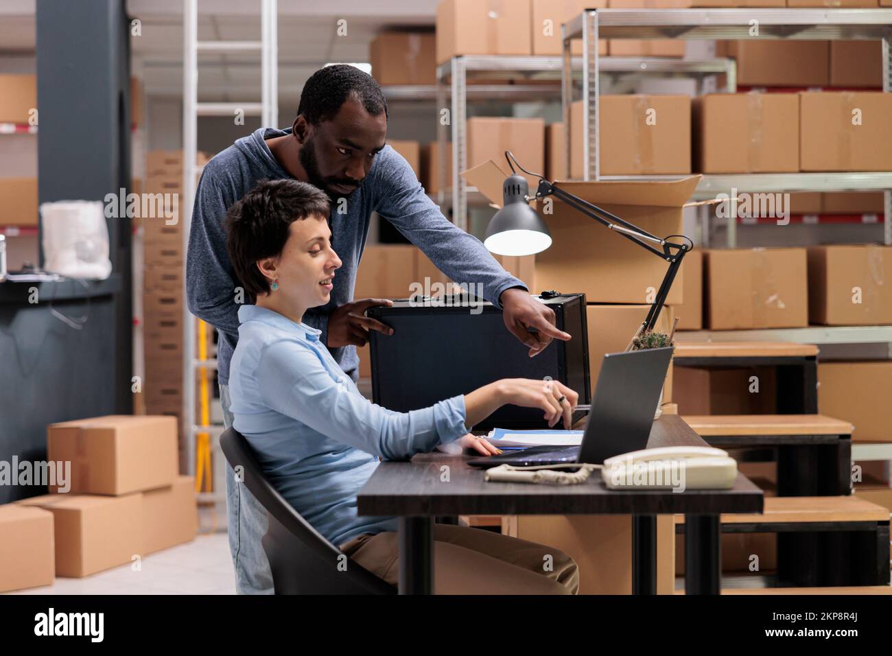 Storehouse manager sitting at desk checking delivery logistics for ...