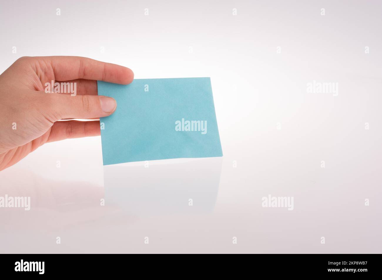 Hand holding a light blue color rectangular paper on a white background ...
