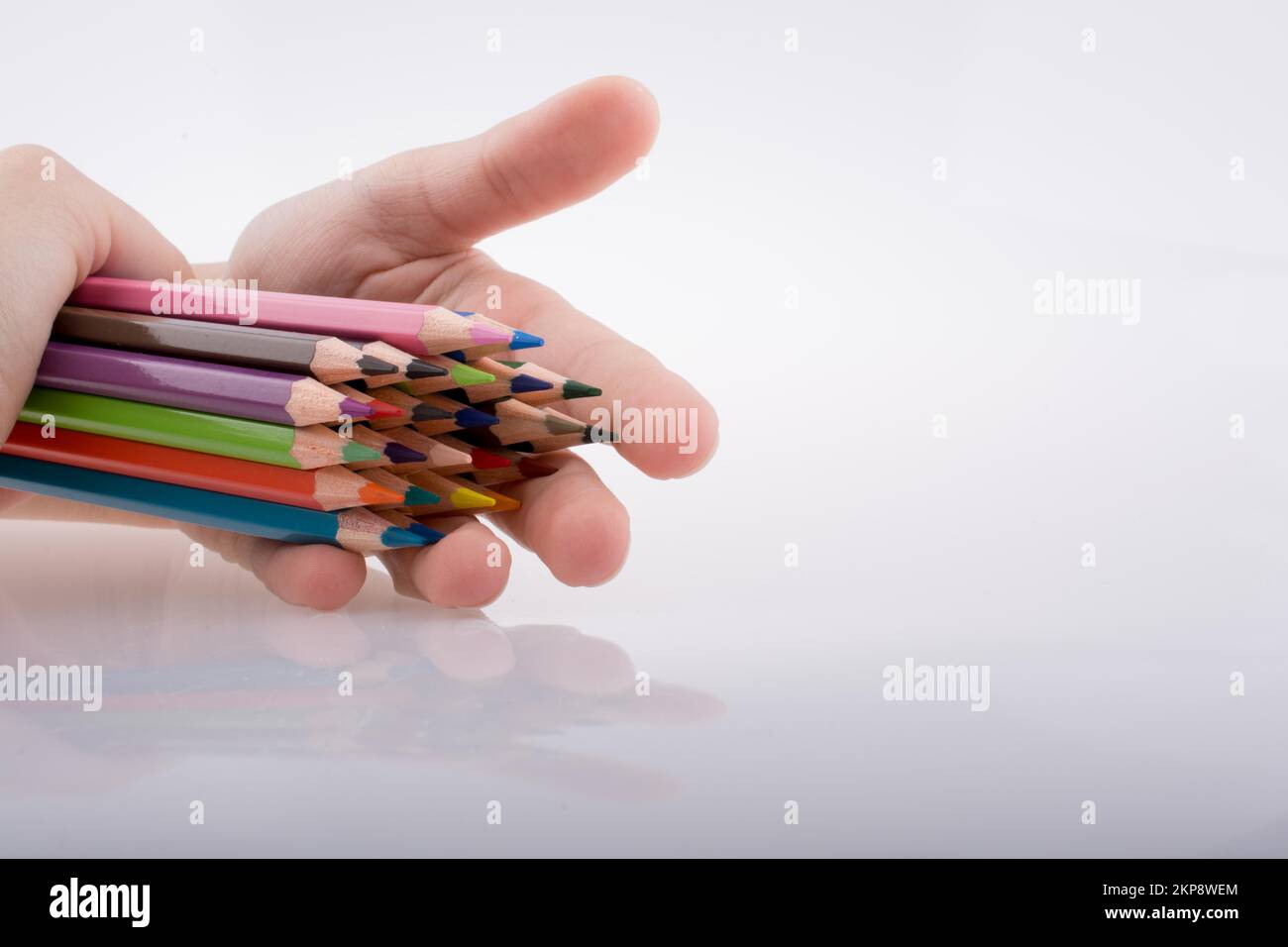 Hand holding color pencils on a white background Stock Photo - Alamy