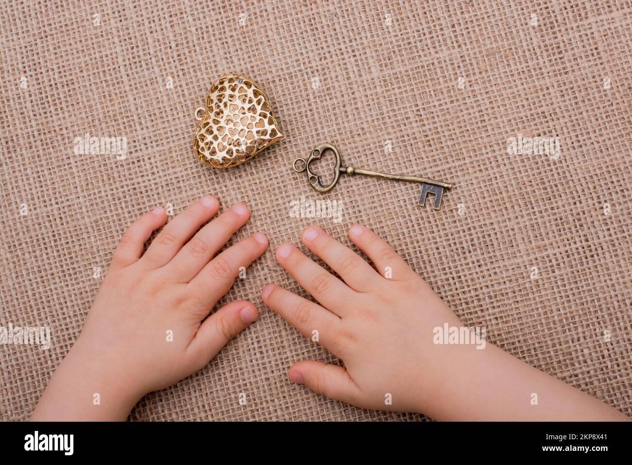 Heart shaped gold color metal object beside a hand Stock Photo - Alamy