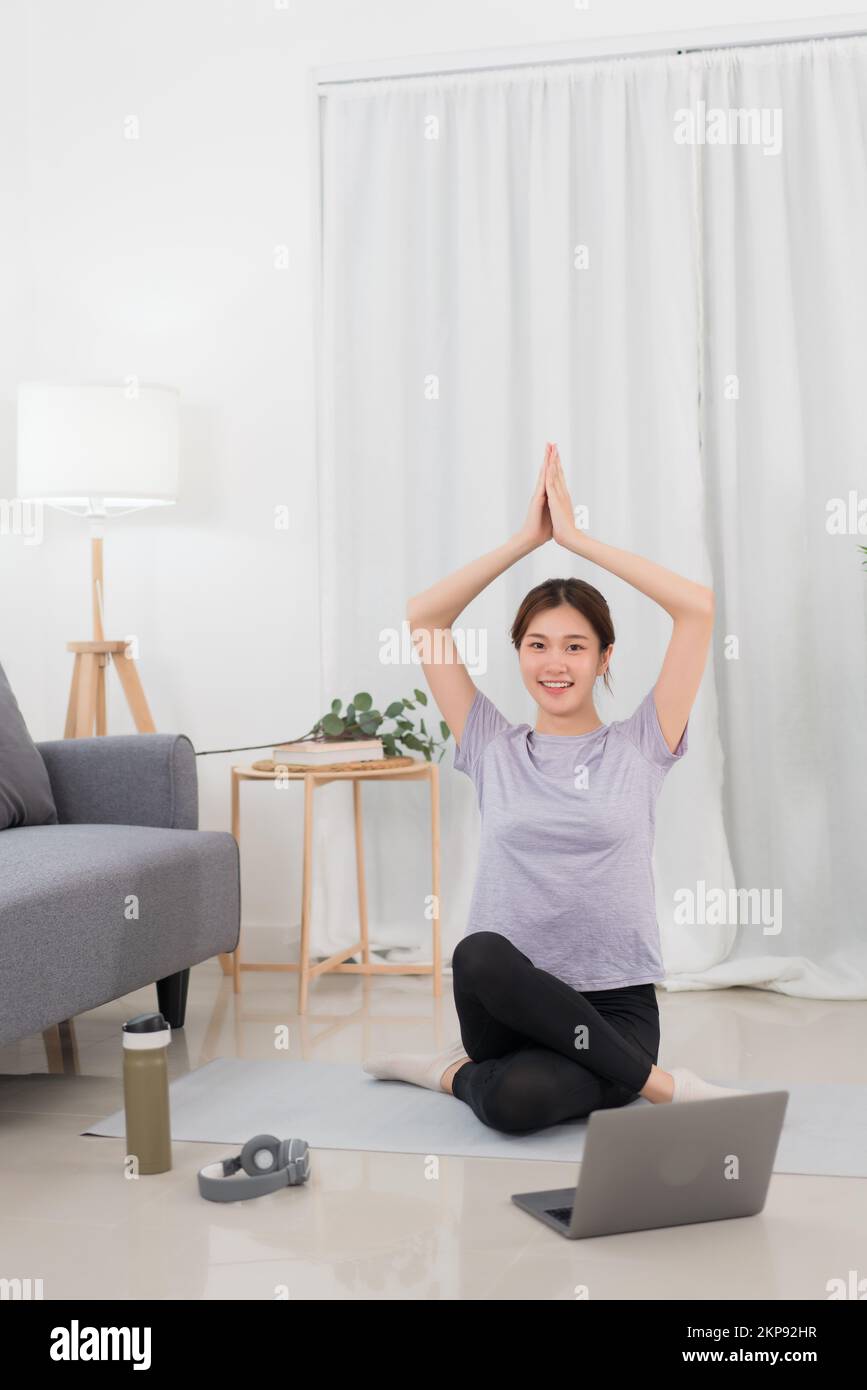 Yoga exercise concept, Asian woman raising arms over head in lotus position while doing yoga ...
