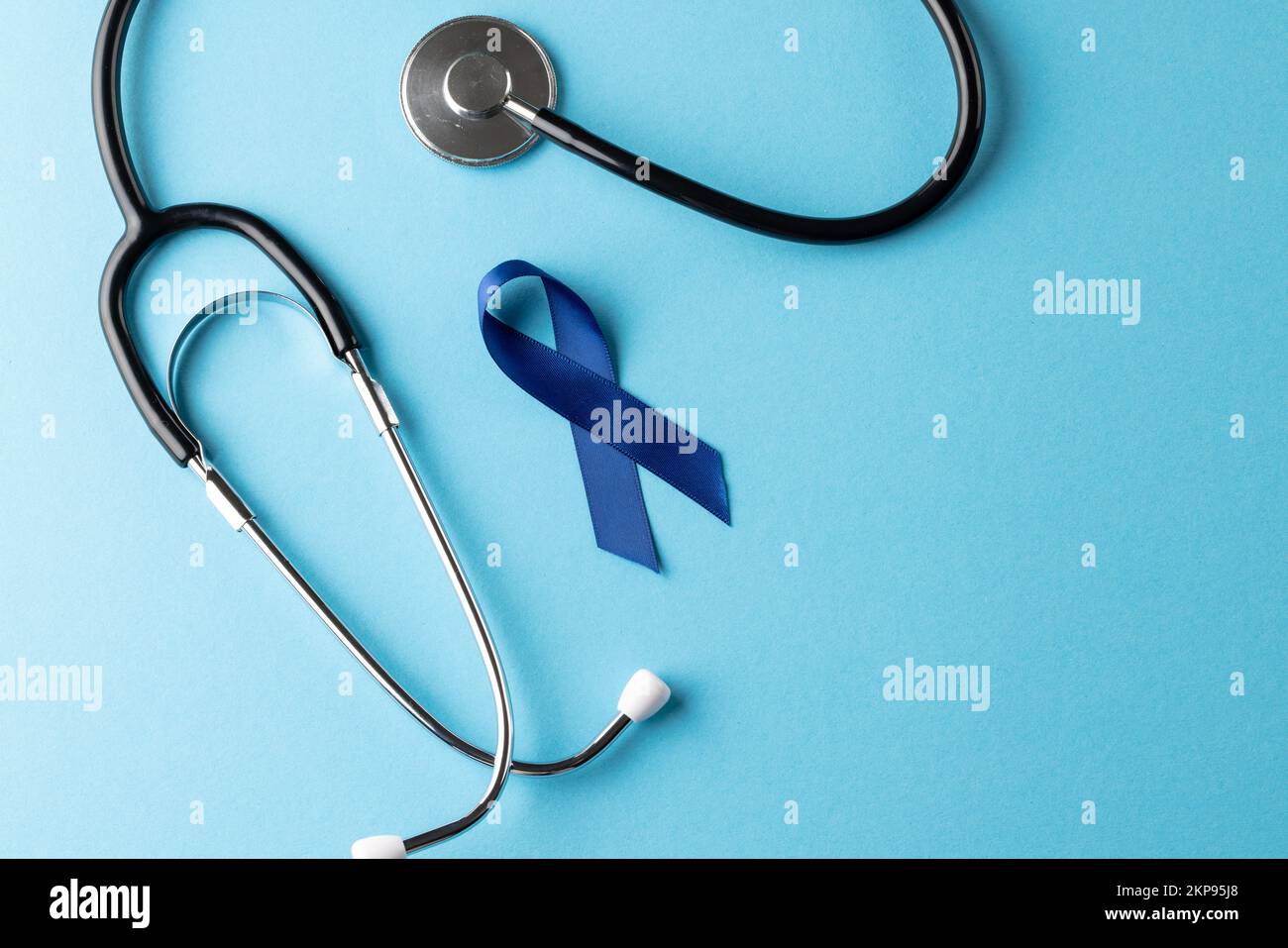 Composition of blue cancer awareness ribbon and stethoscope on blue ...