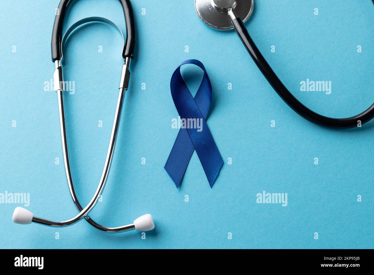 Composition of blue cancer awareness ribbon and stethoscope on blue ...