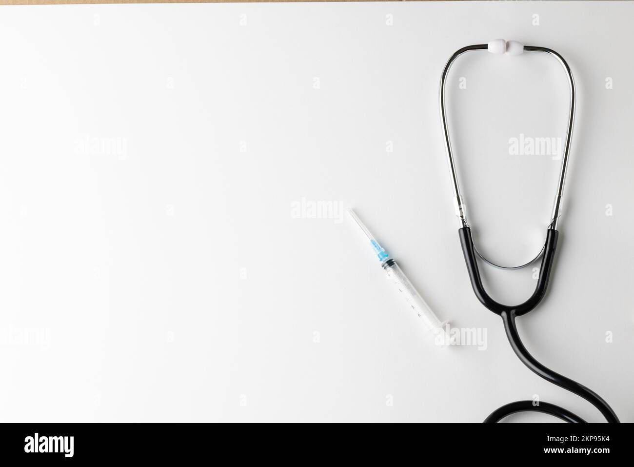 Composition of stethoscope with syringe on white background with copy ...