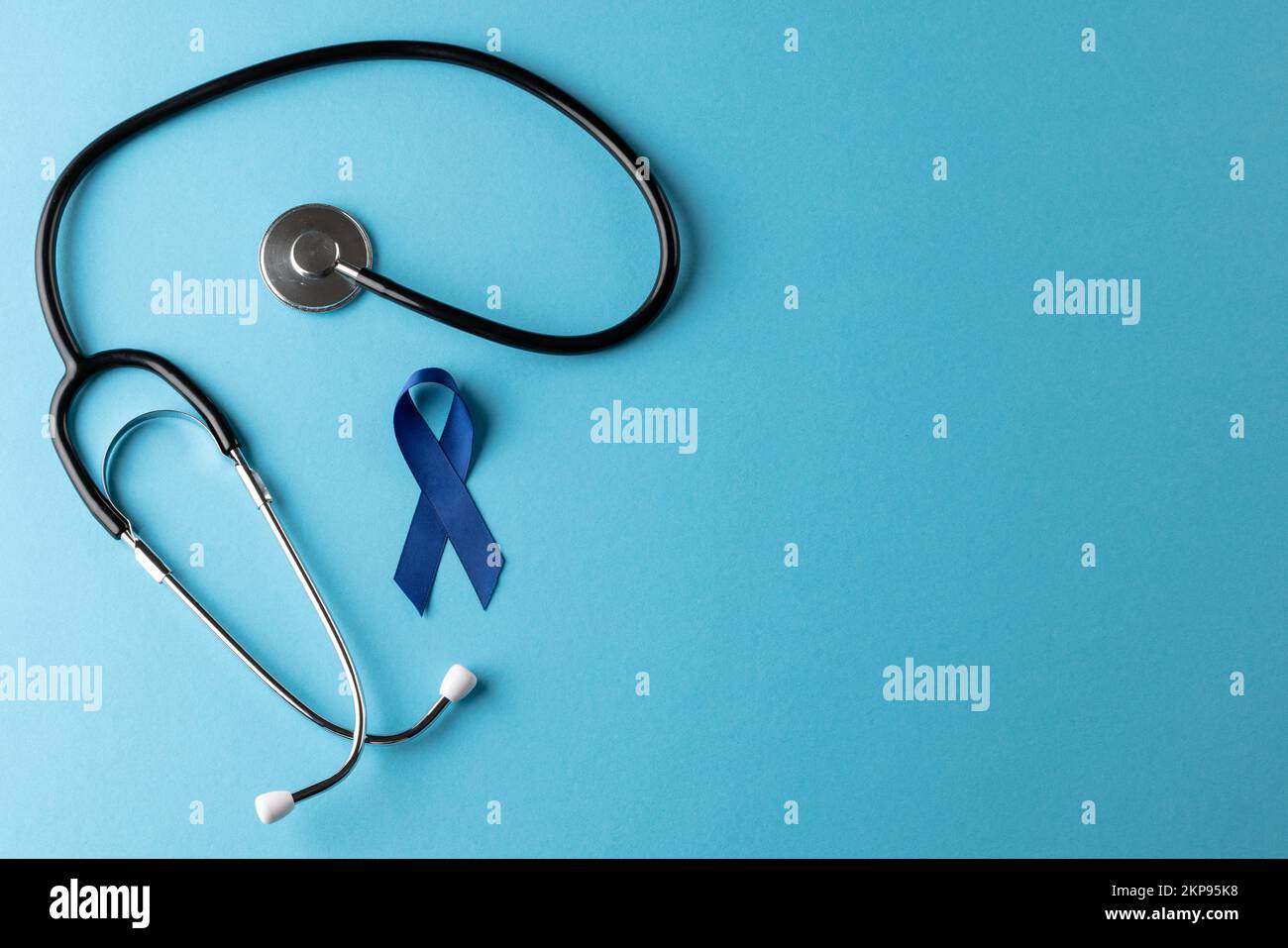 Composition of blue cancer awareness ribbon and stethoscope on blue ...