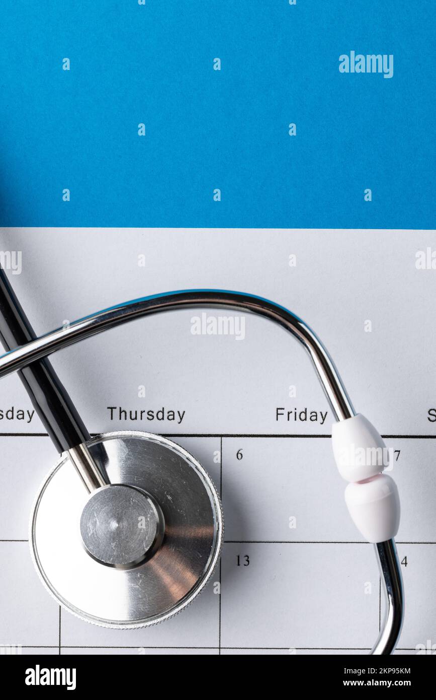 Vertical composition of stethoscope with calendar on blue background ...