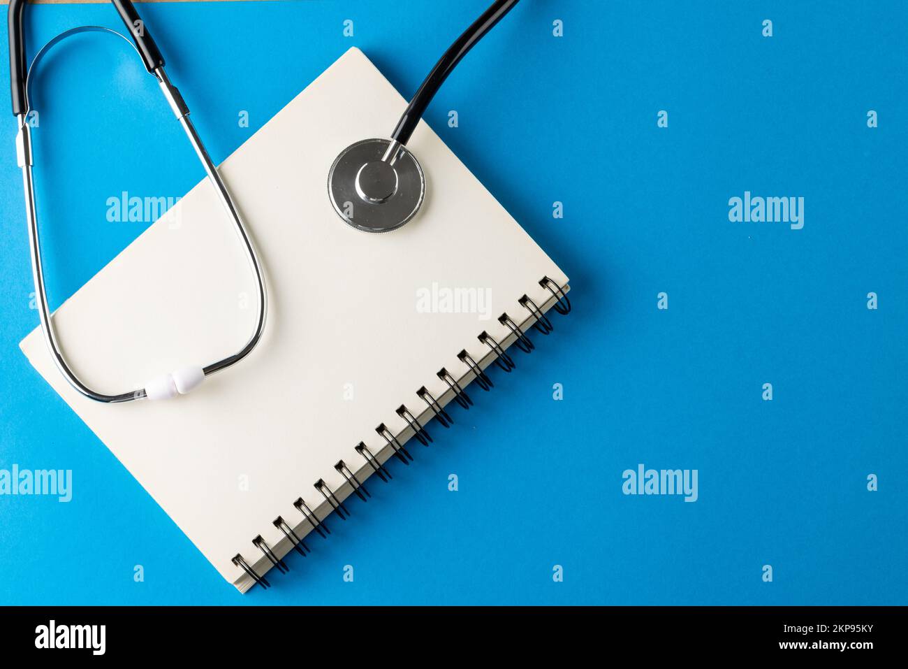 Composition of stethoscope with notebook on blue background with copy ...