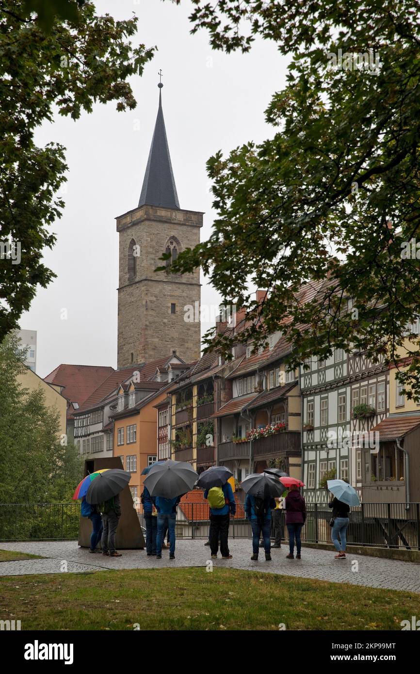 Group of people in the rain in front of half-timbered houses of the ...