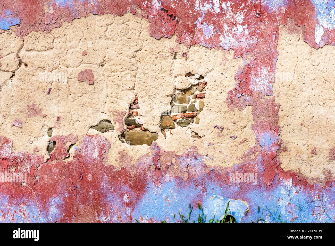 Old painted plaster wall outside, paint in many colours peeling off ...