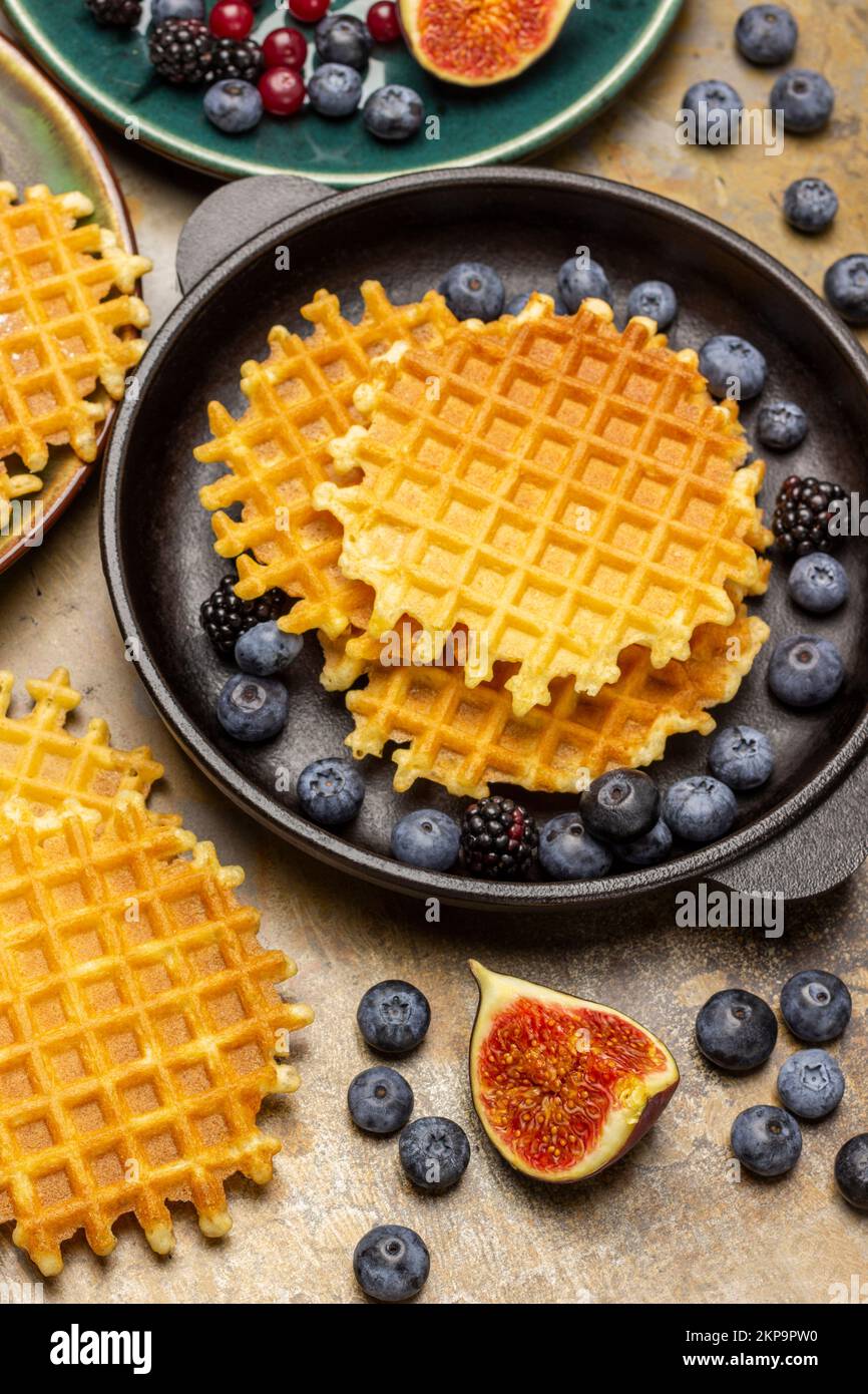 Crispy waffles and berries in a frying pan. Half a fig, blueberries and waffles. Flat lay. Rusty ...