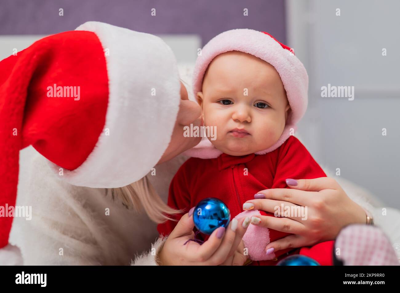 Caucasian woman hugging baby son in santa claus costume Stock Photo - Alamy