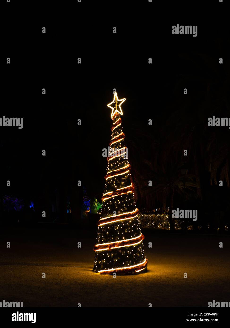 Conical Christmas tree decorated with bright fairy lights and star ...