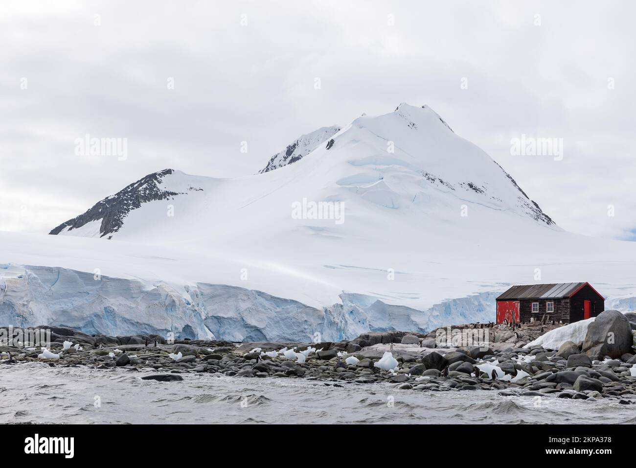 Ashore of the ocean with a building on it and mountains covered with ...