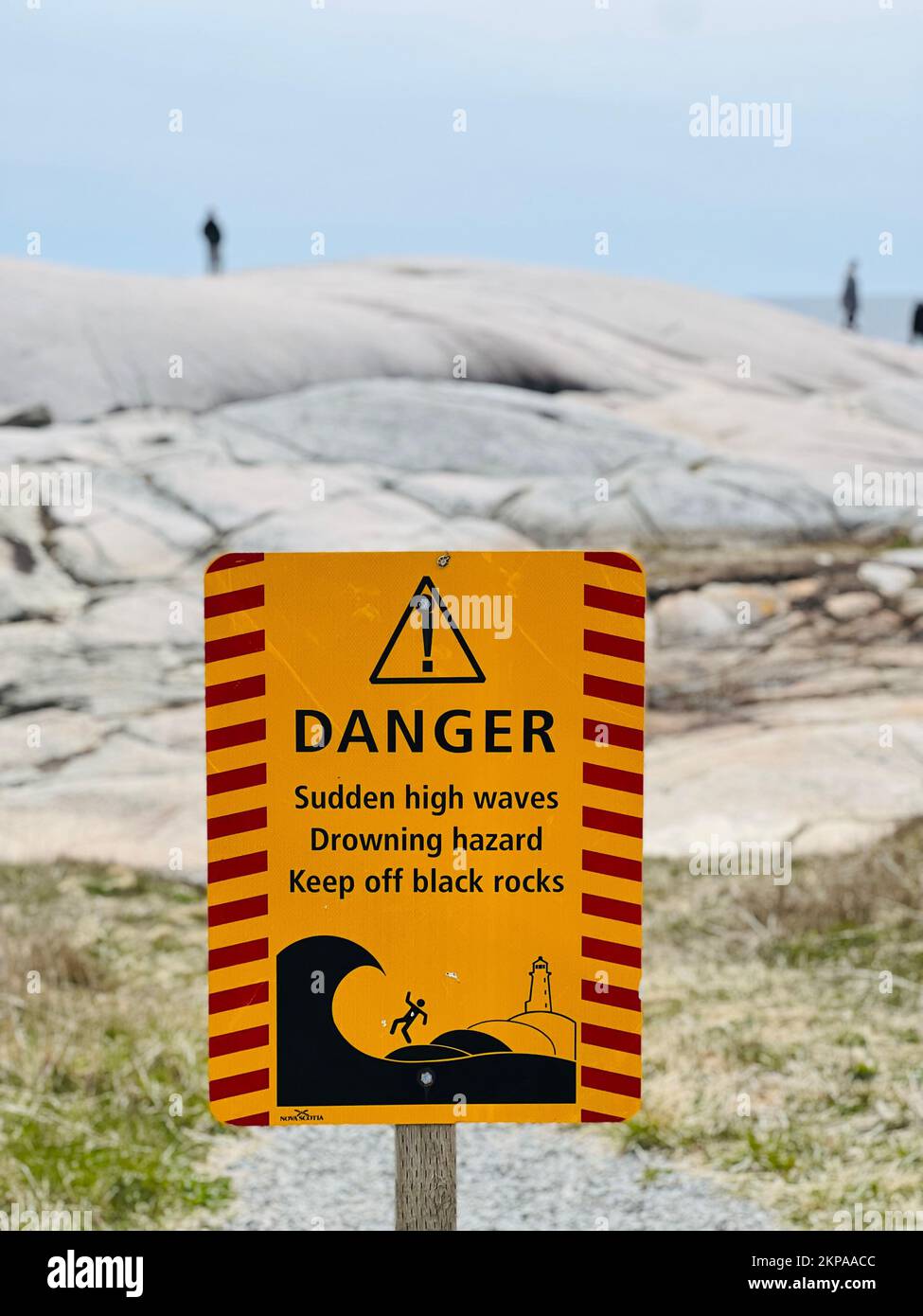 A vertical closeup of a warning sign to keep off black rocks at Peggy's ...
