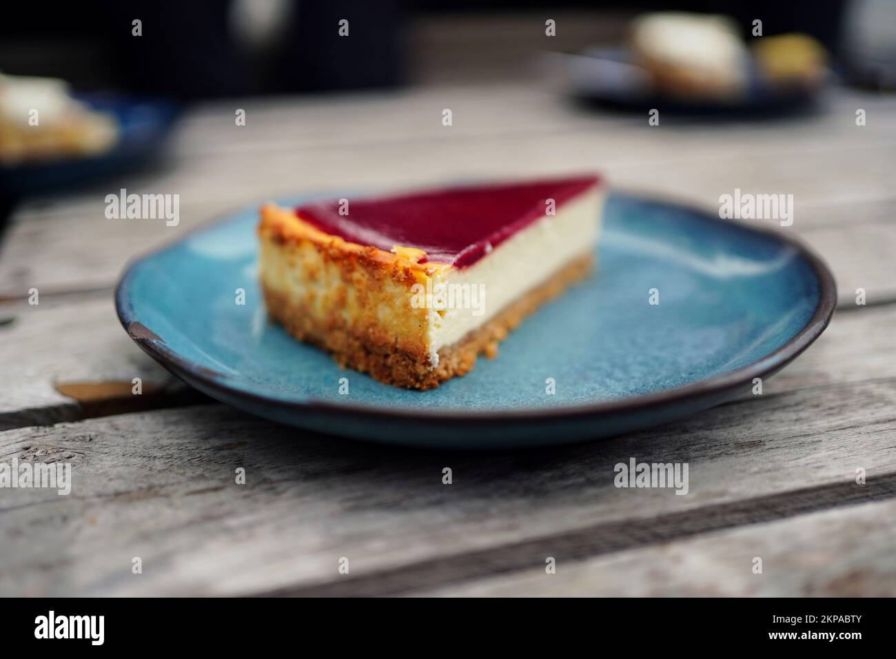 piece of cheesecake with a raspberry fruit glaze on a blue plate on a ...