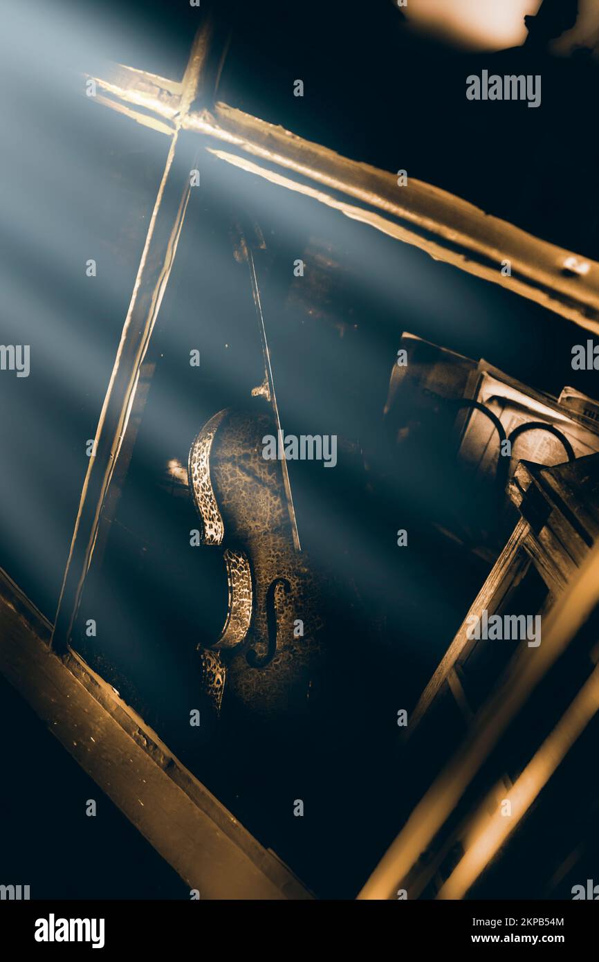 Sad blue toned photo of a violin lit by morning sun rays in a dark ...