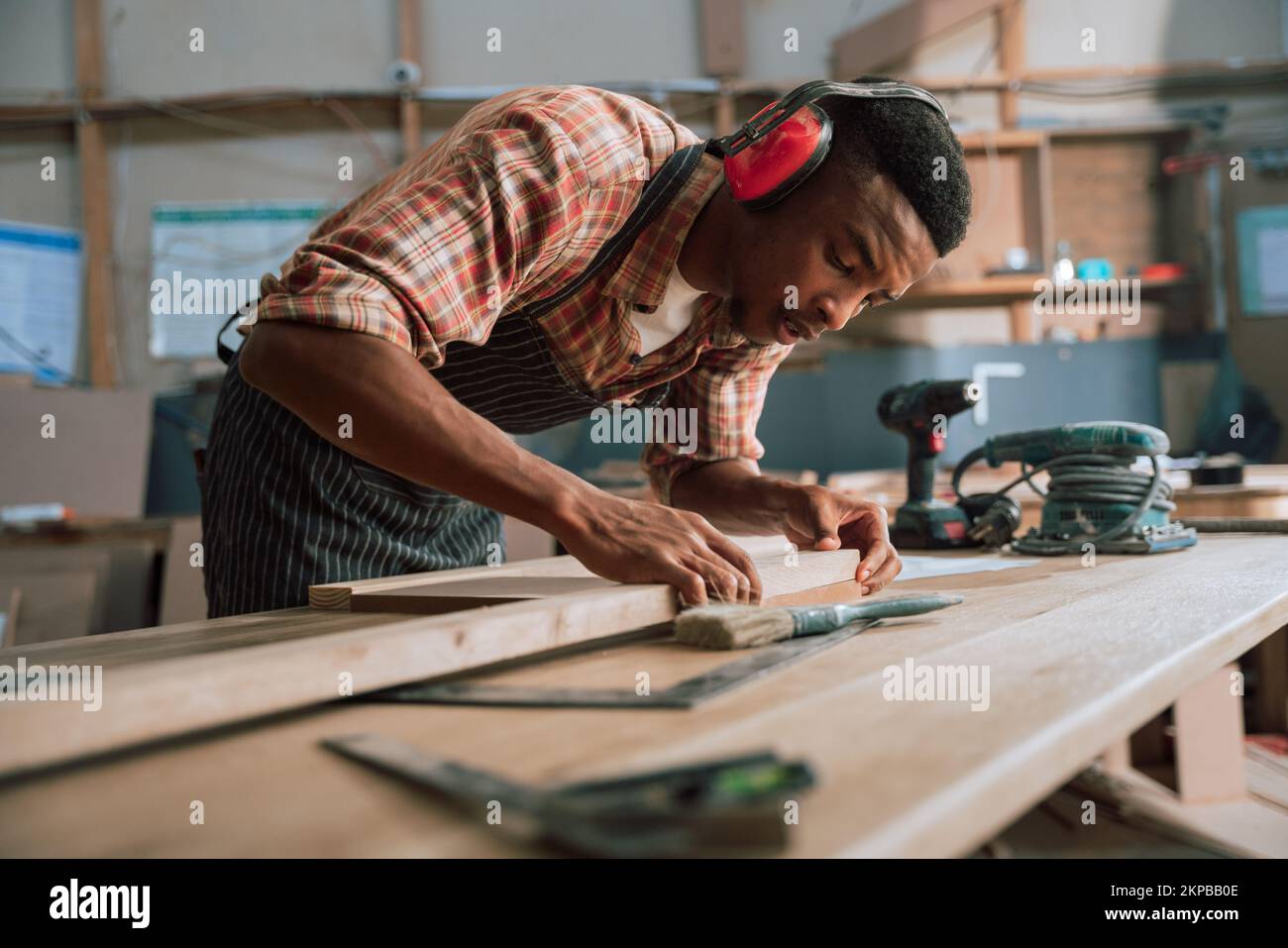 African carpenter measuring wood and timber with electric tools Stock ...