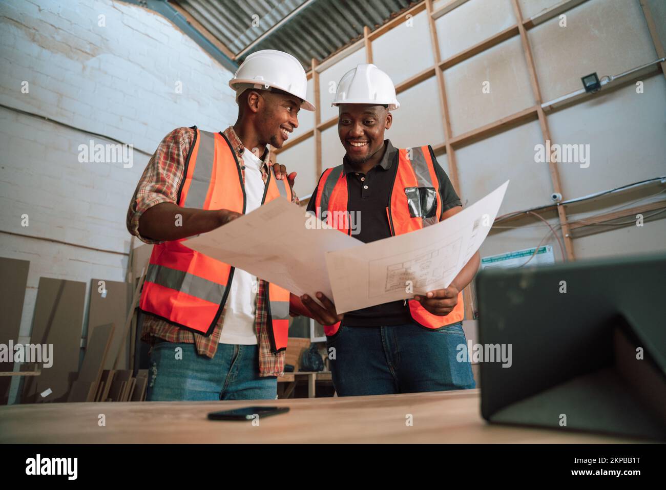 African factory owners working together in workshop looking at design ...