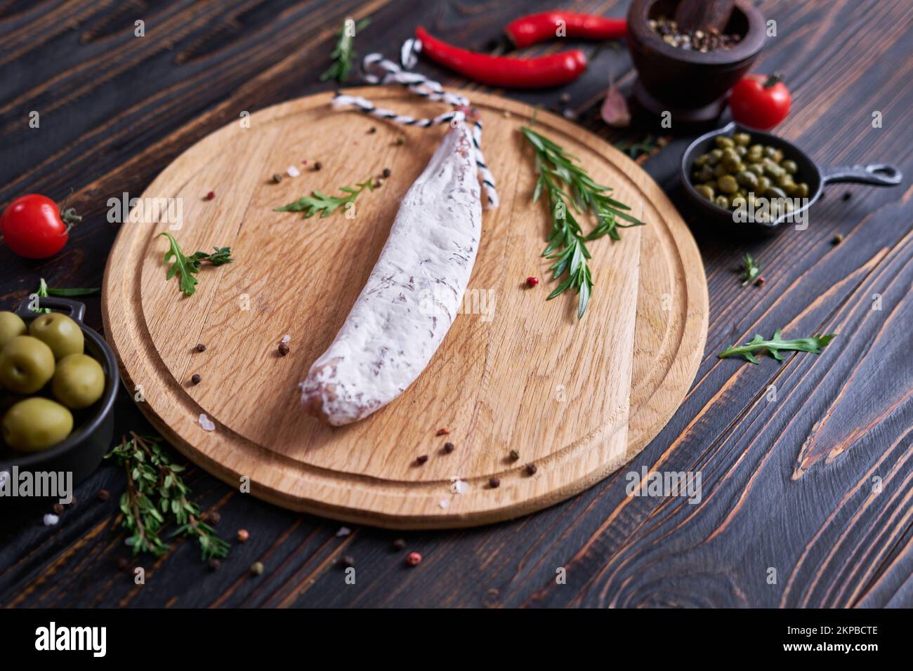 Spanish fuet salami sausageon wooden cutting board at domestic kitchen ...