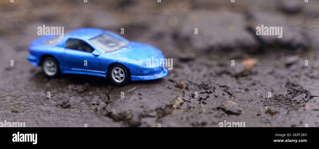 Natural disasters. A blue car drives along a road destroyed by a ...