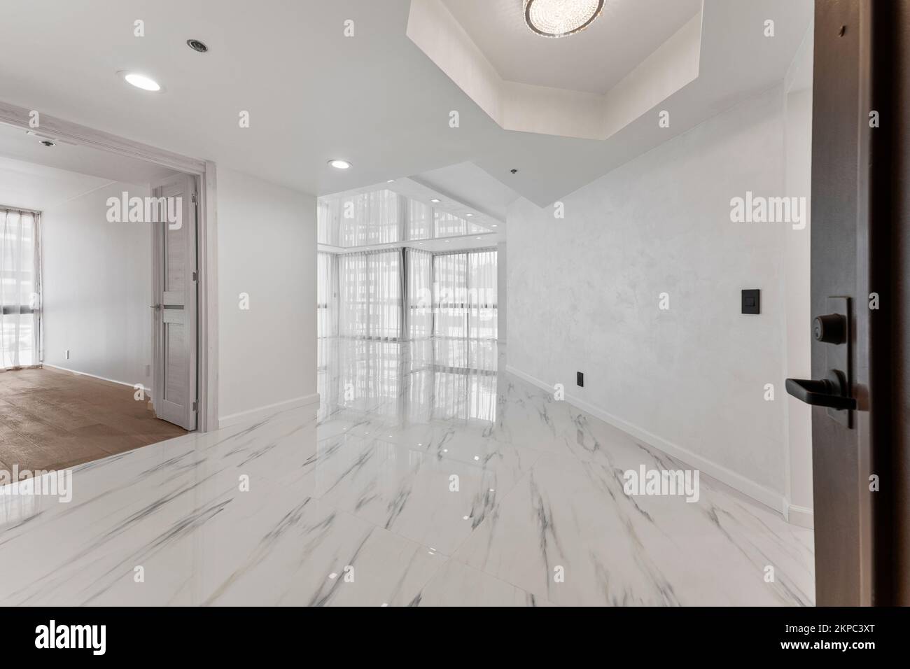 A large and sunny corridor with marble tiles and white walls in modern ...
